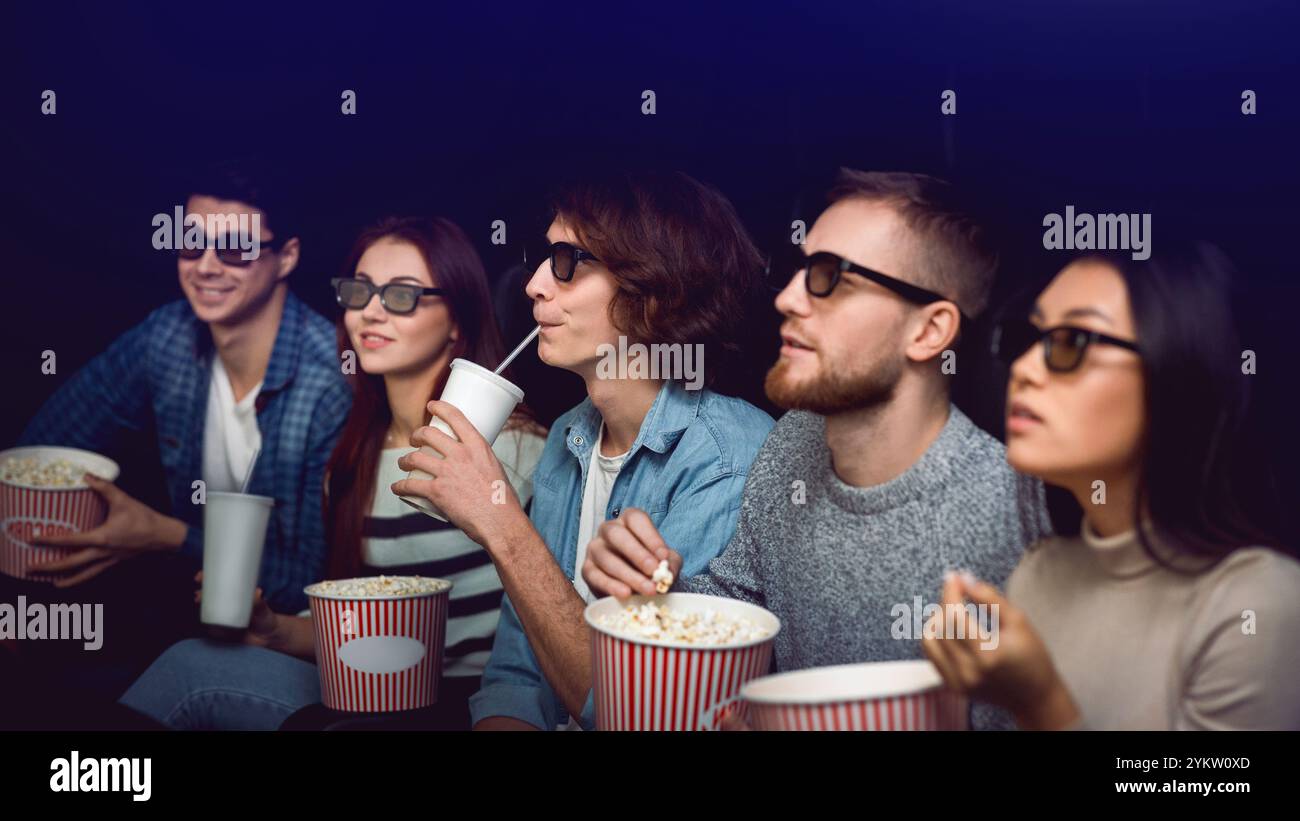 Premiere night. Young people with snacks watching 3D movie in cinema ...
