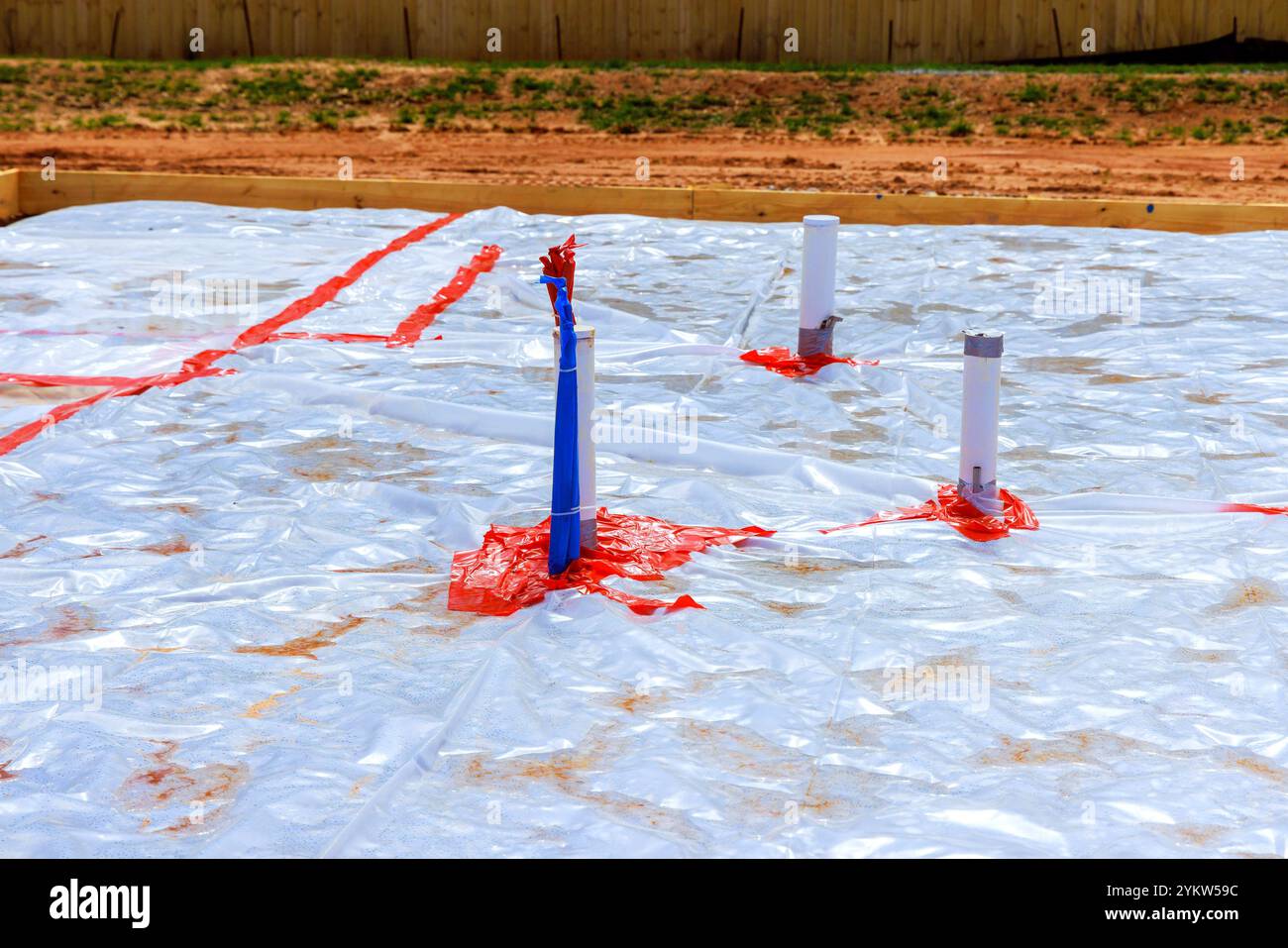 Workers prepare for foundation work by laying plastic sheeting pipes at ...