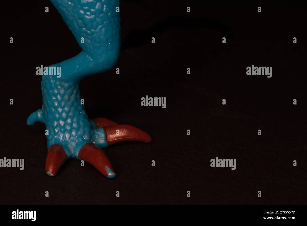 Large blue dinosaur or monster leg with long brown claws on a black ...