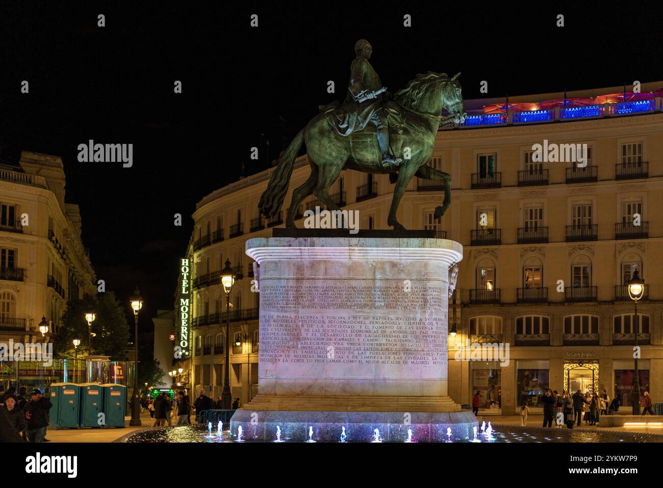 A bronze statue of a mounted figure on a pedestal, illuminated at night ...