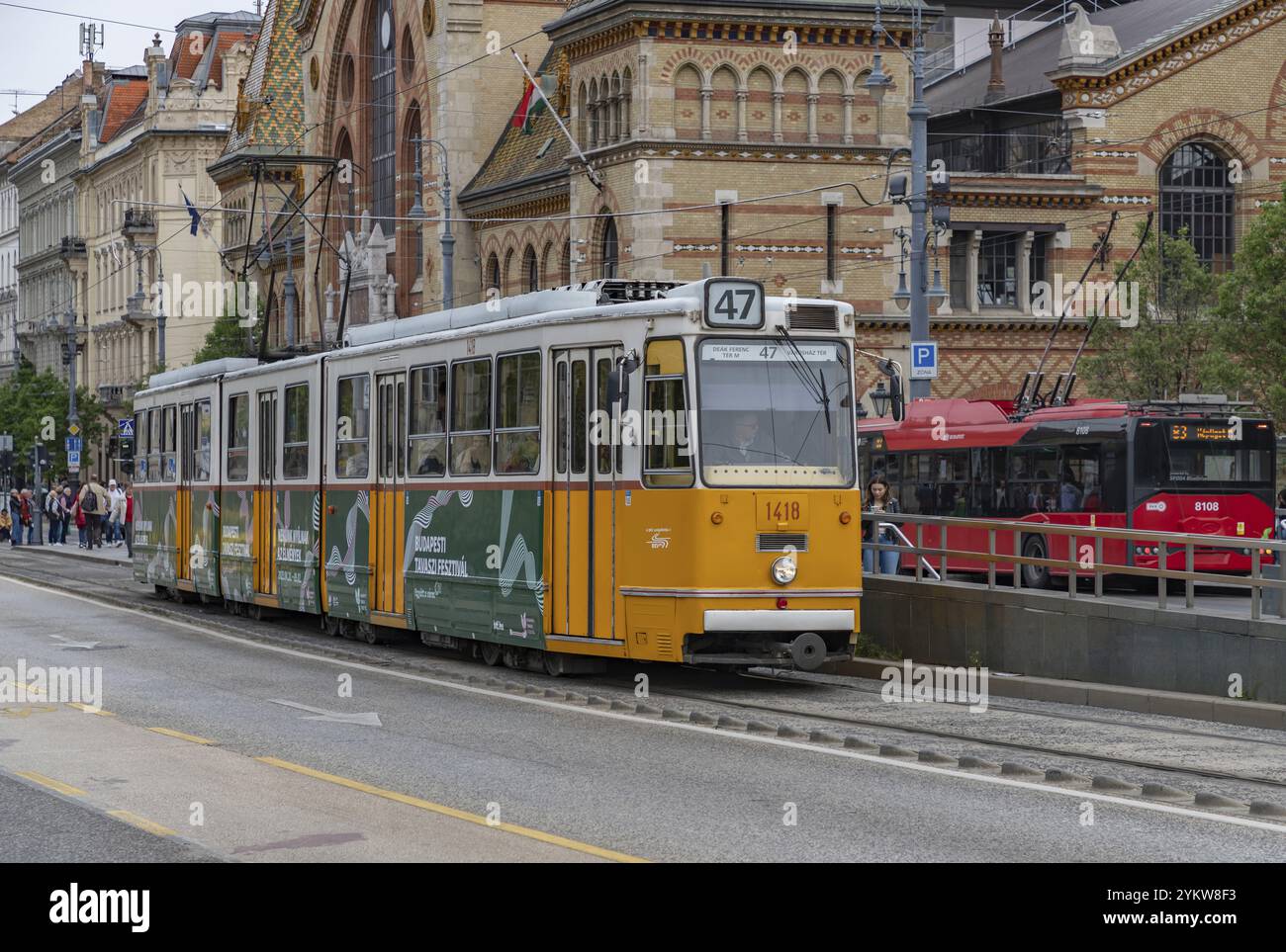 A picture of a yellow Budapest tram next to the Central Market Hall ...