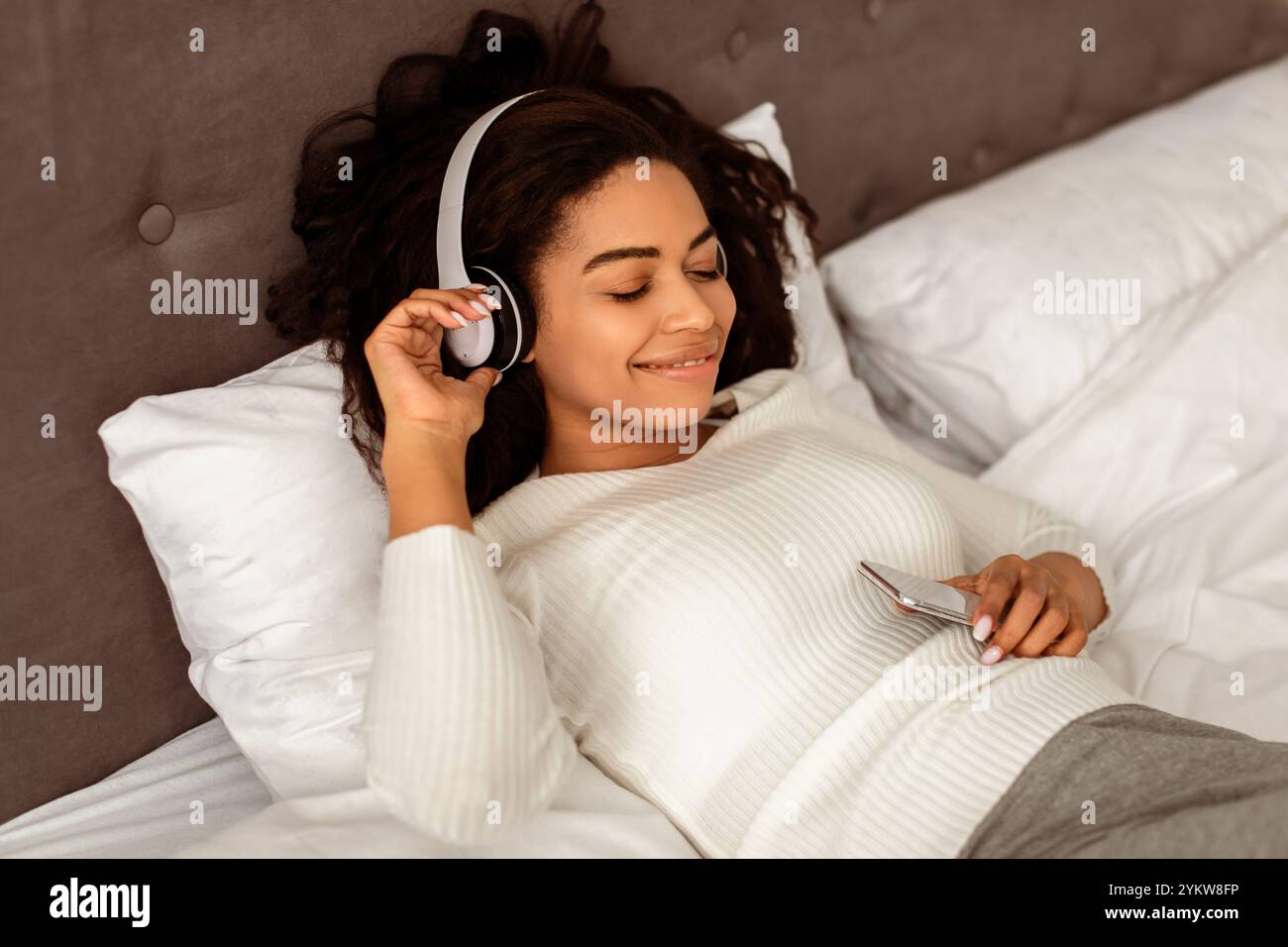Satisfied young black woman listening to music Stock Photo - Alamy