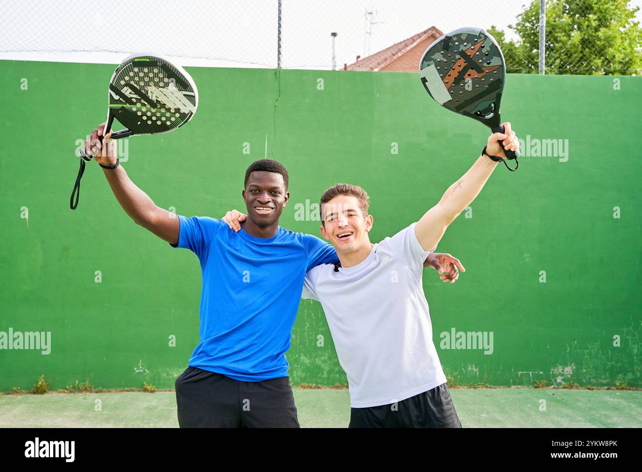 Two men are holding paddle tennis rackets and smiling. They are posing ...