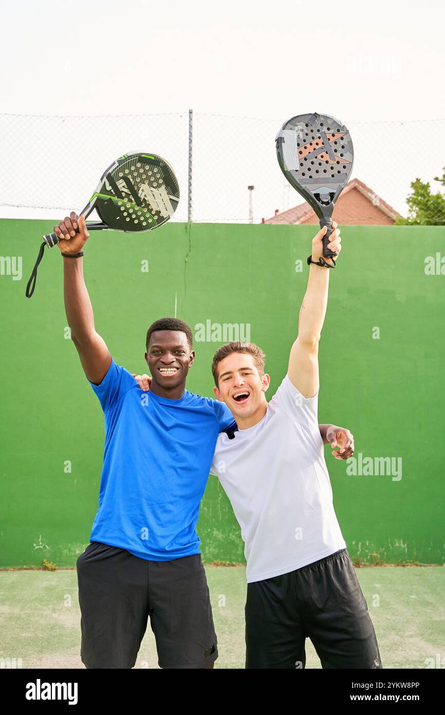 Two men are holding paddle tennis rackets and smiling. They are posing ...