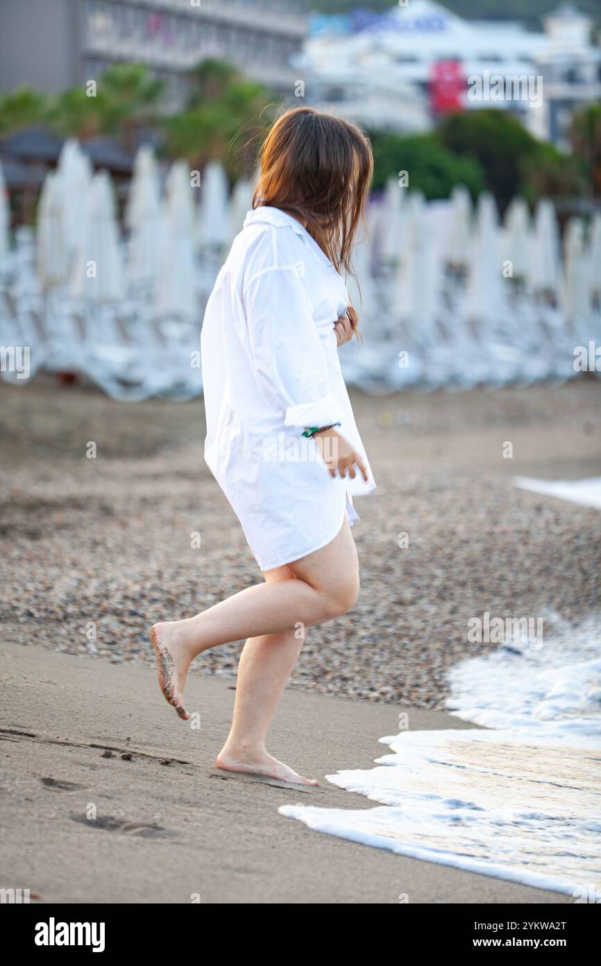 A charming young red-haired woman in a bikini and a translucent light ...