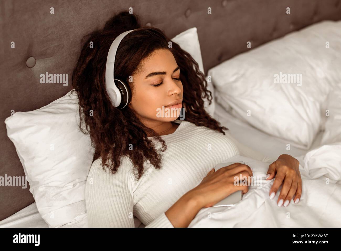 Satisfied young black woman listening to music Stock Photo - Alamy