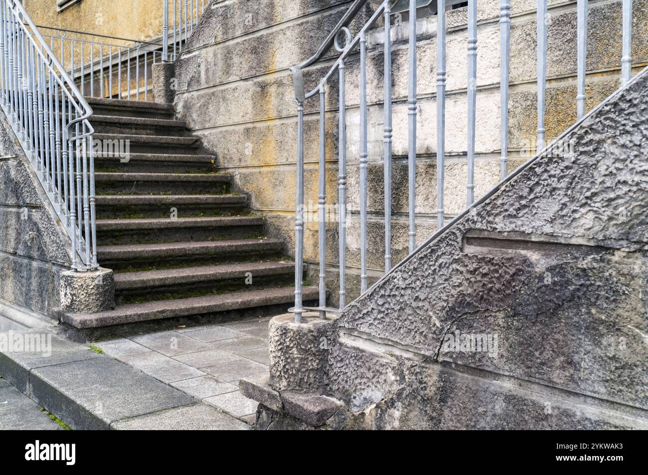 Weathered stone steps with a metal railing create access to a building ...