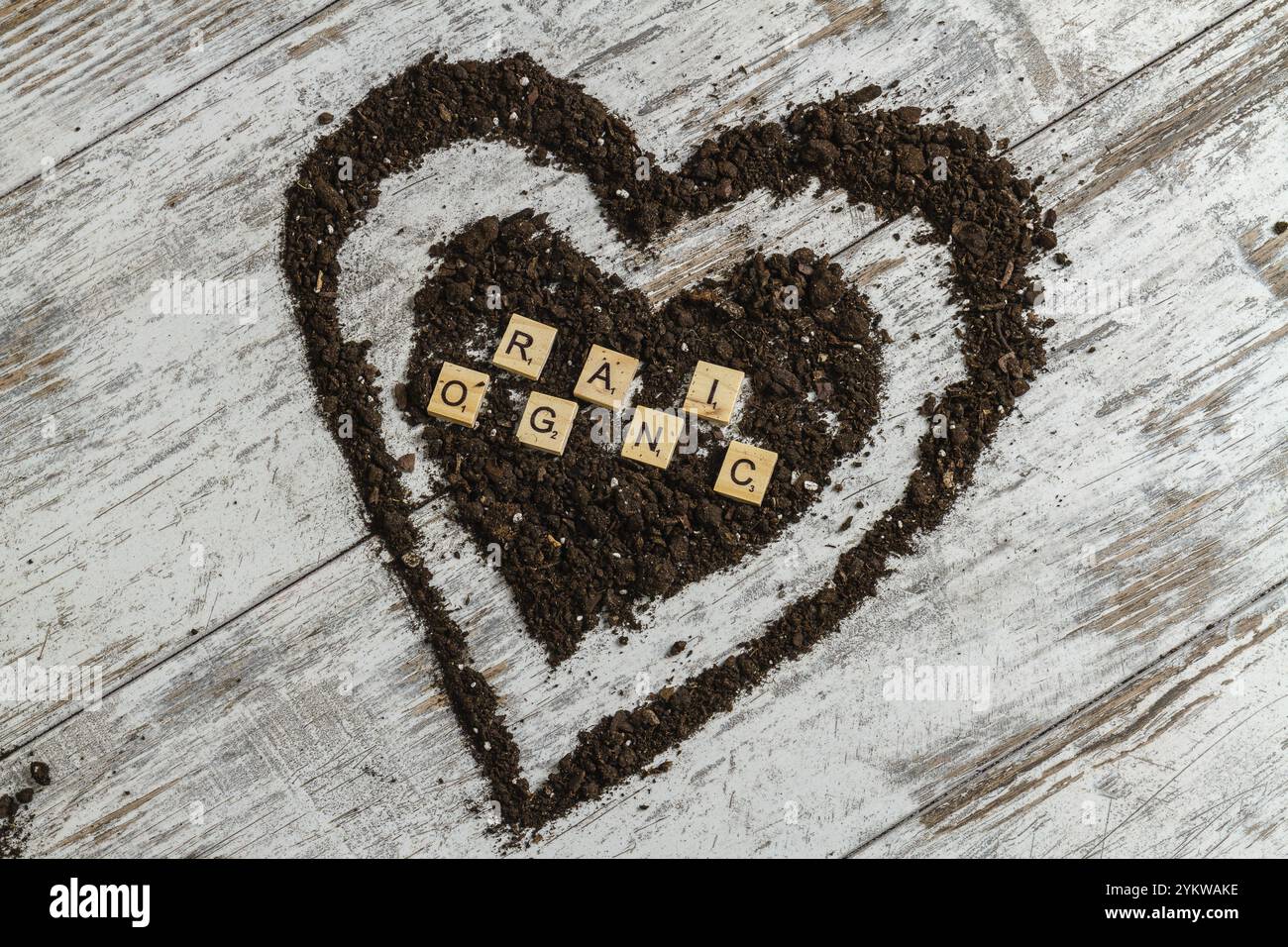 Natural black soil in a heart shape and word organic. Gray desk ...