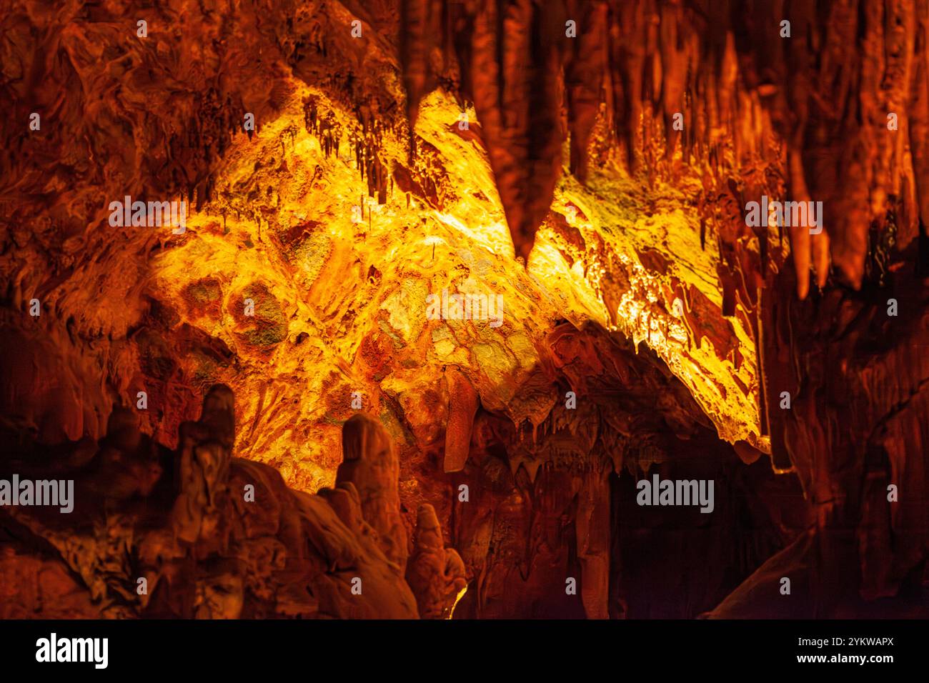 Stalactites and stalagmites in a cave illuminated by multi-colored ...