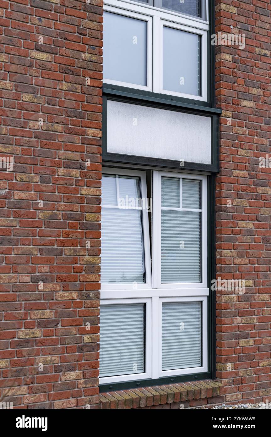 Opened window with lowered venetian blinds on red brick wall allowing ...