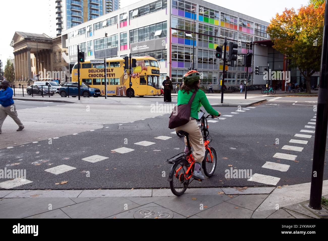 Young woman student cyclist crossing road riding bike outdide UAL ...