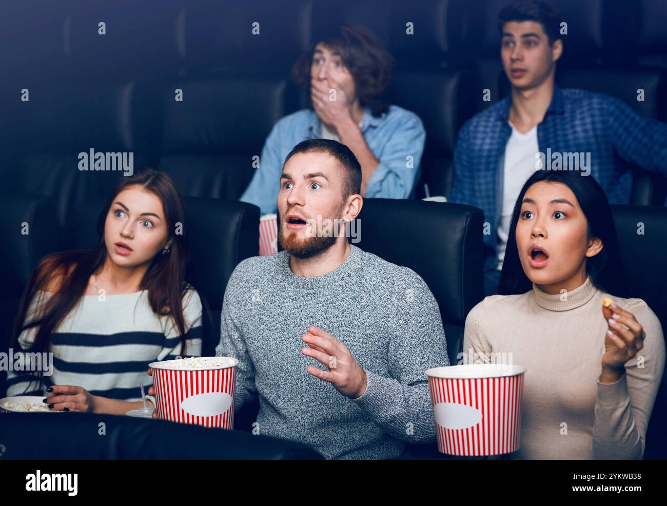 Scared young people watching new motion picture in movie theater Stock ...