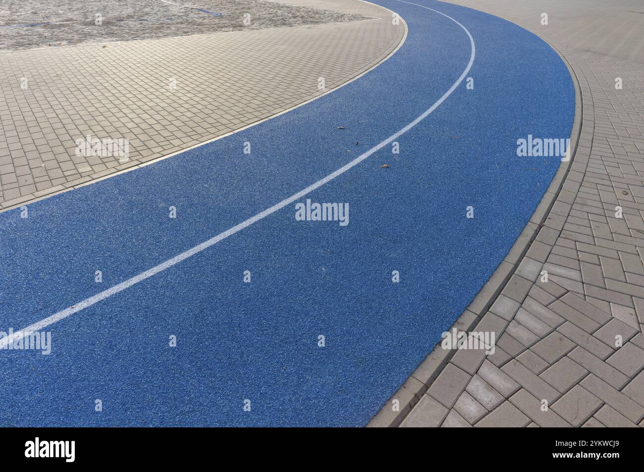 Blue running track curve with white lines surrounded by paving stones ...