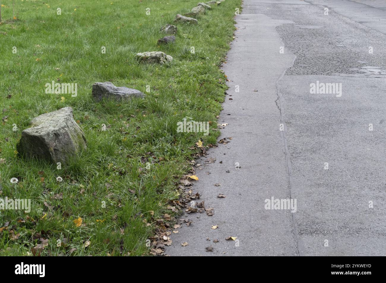 Stones lining the edge of a grassy area next to an asphalt road ...