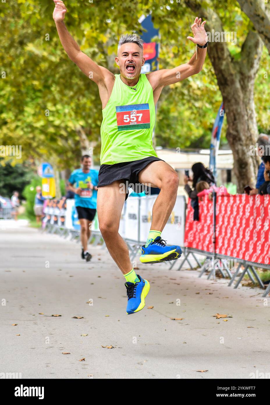 Energetic male runner jumping with joy during marathon race ...