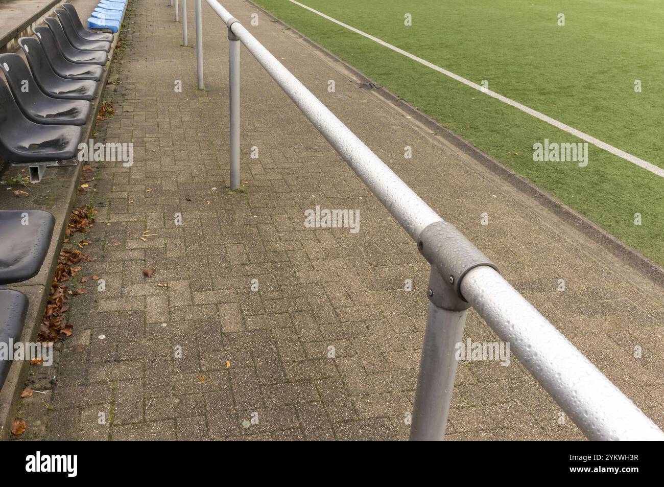 Empty black bleacher seats and a shiny metal railing are overlooking an ...