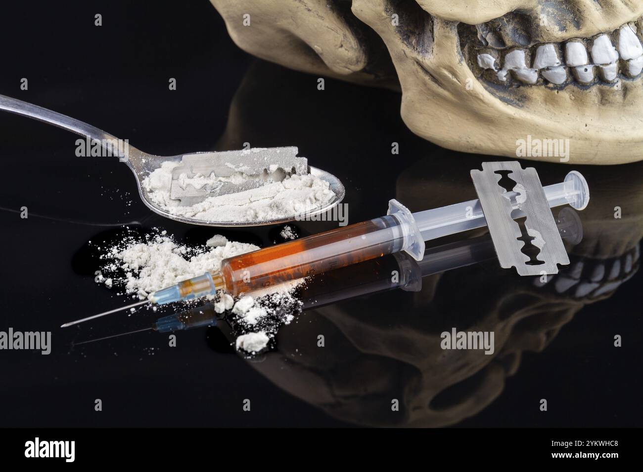 Close-up syringe with white powder and razors on black reflective table ...