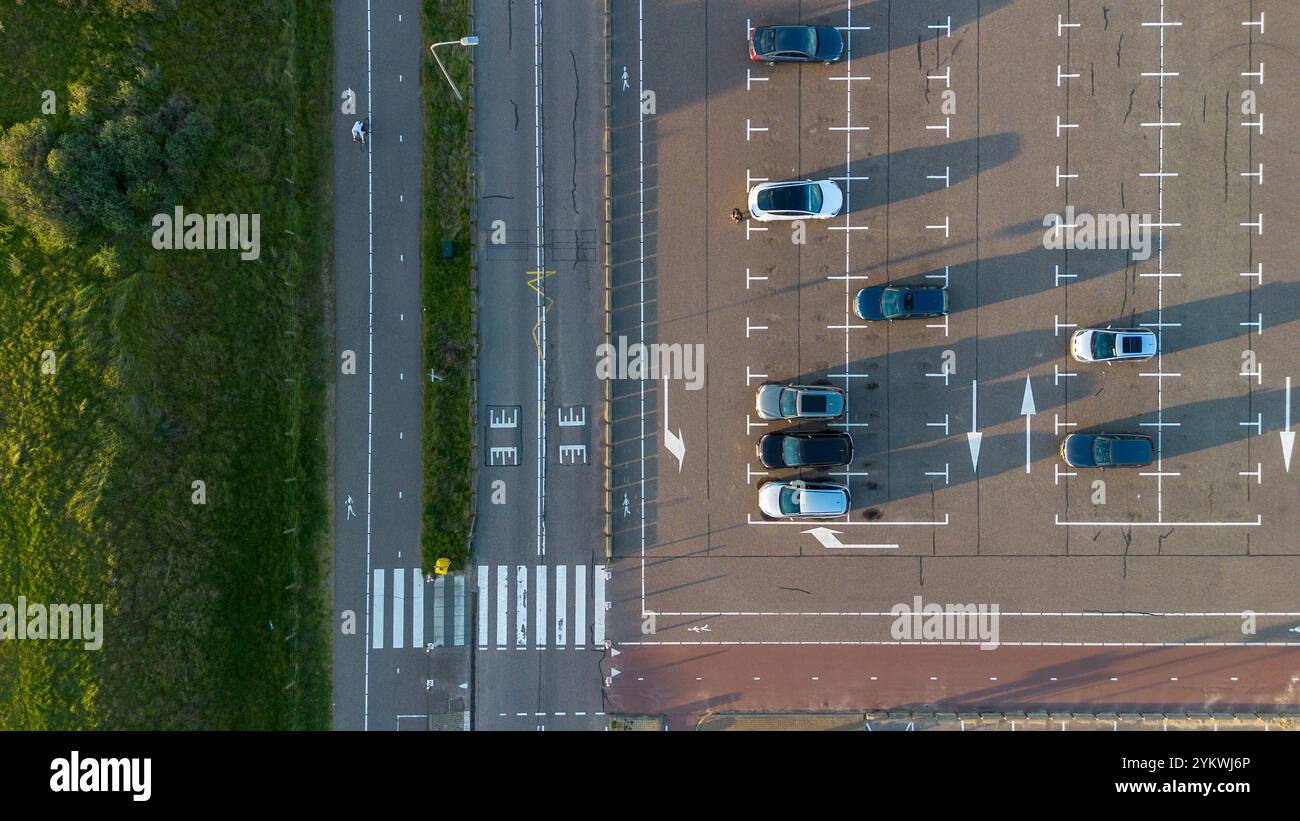 Aerial view of a parking lot with parked cars casting long shadows ...