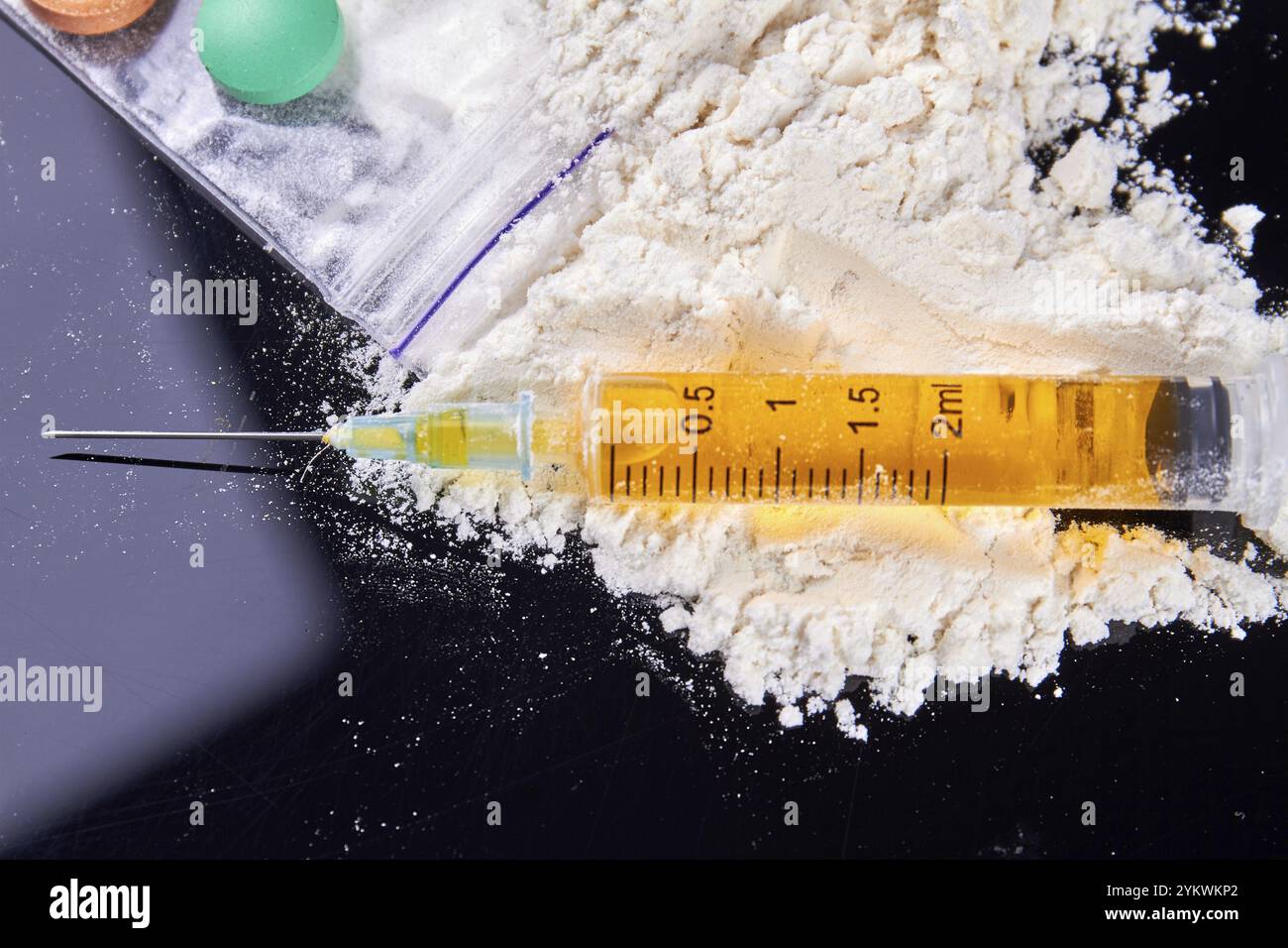 Syringe filled with drug dose on the pile of white powder. Drug ...