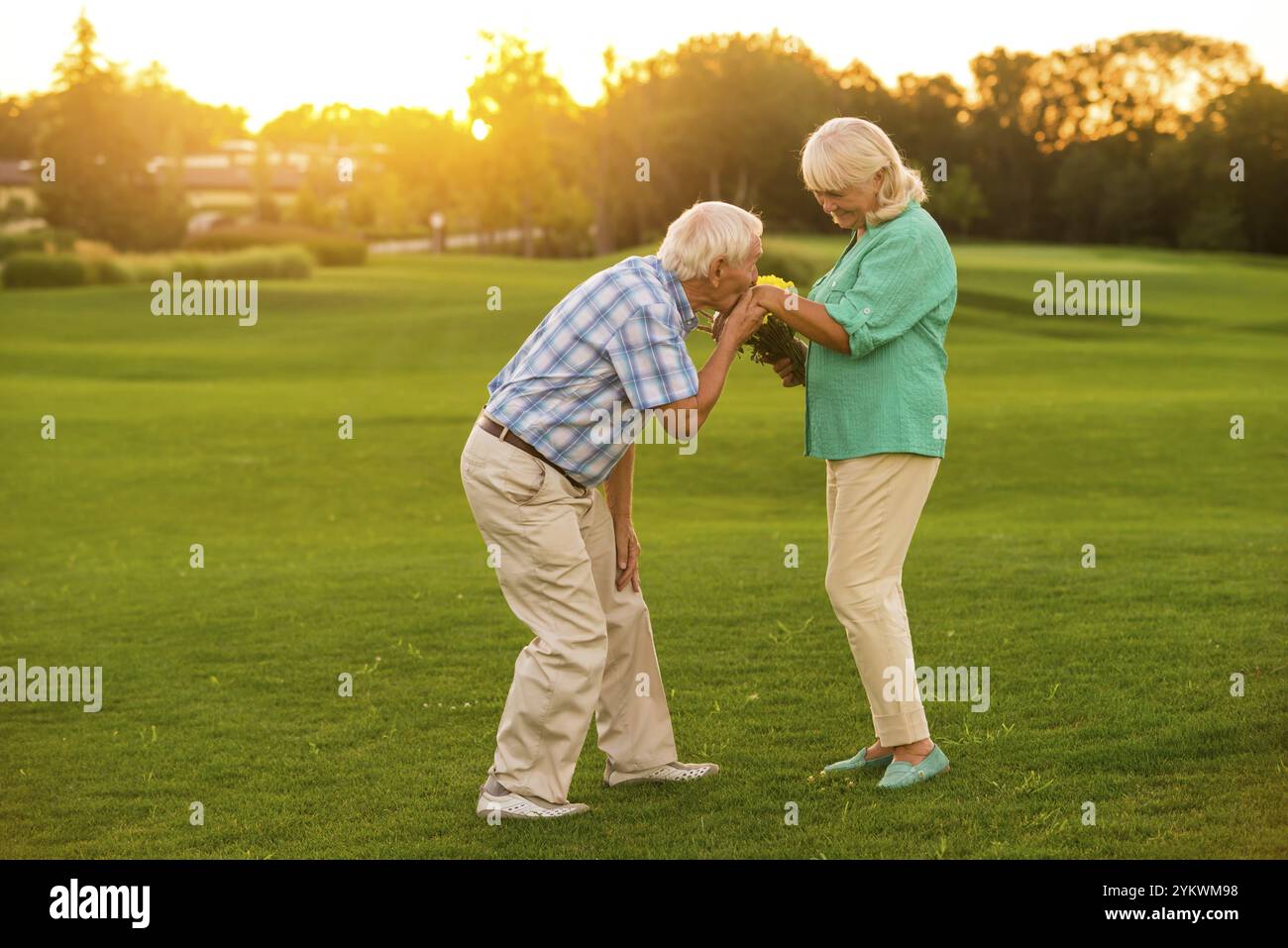 Senior man kissing woman's hand. Couple standing on a meadow. Loving ...