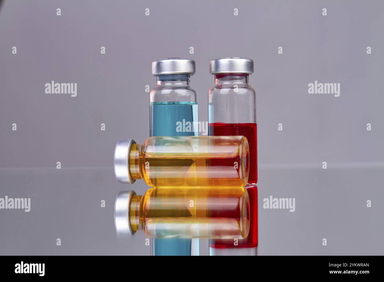 Collection of glass drug vials with colored medicine. Reflective ...