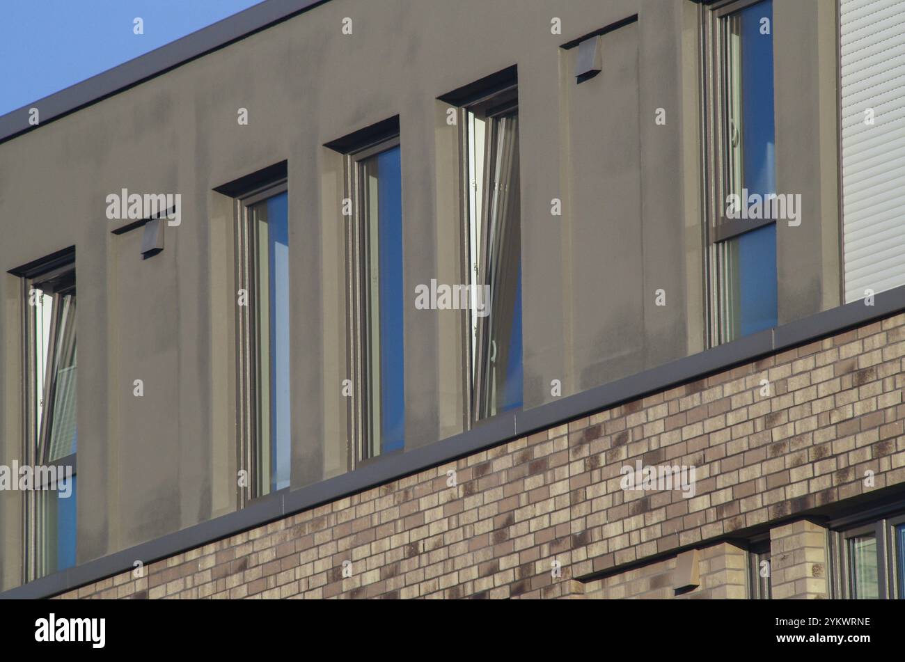 Open windows on a modern building reflecting blue sky, featuring a brick facade Stock Photo - Alamy