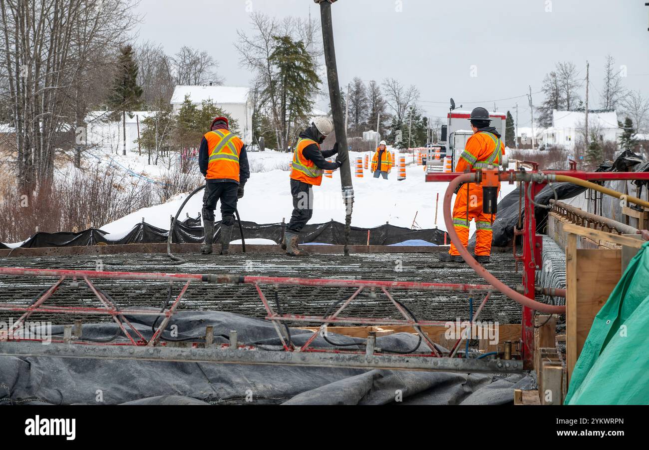 Workers pouring concrete using a concrete pump to build a slab, winter ...