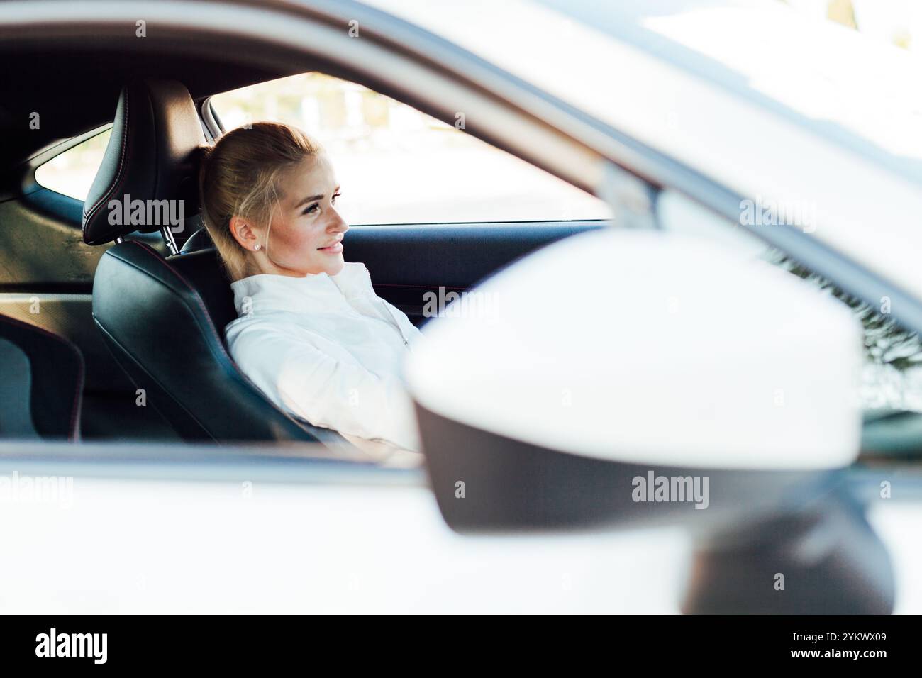 Beautiful woman driver sitting behind the wheel of a white car on the ...