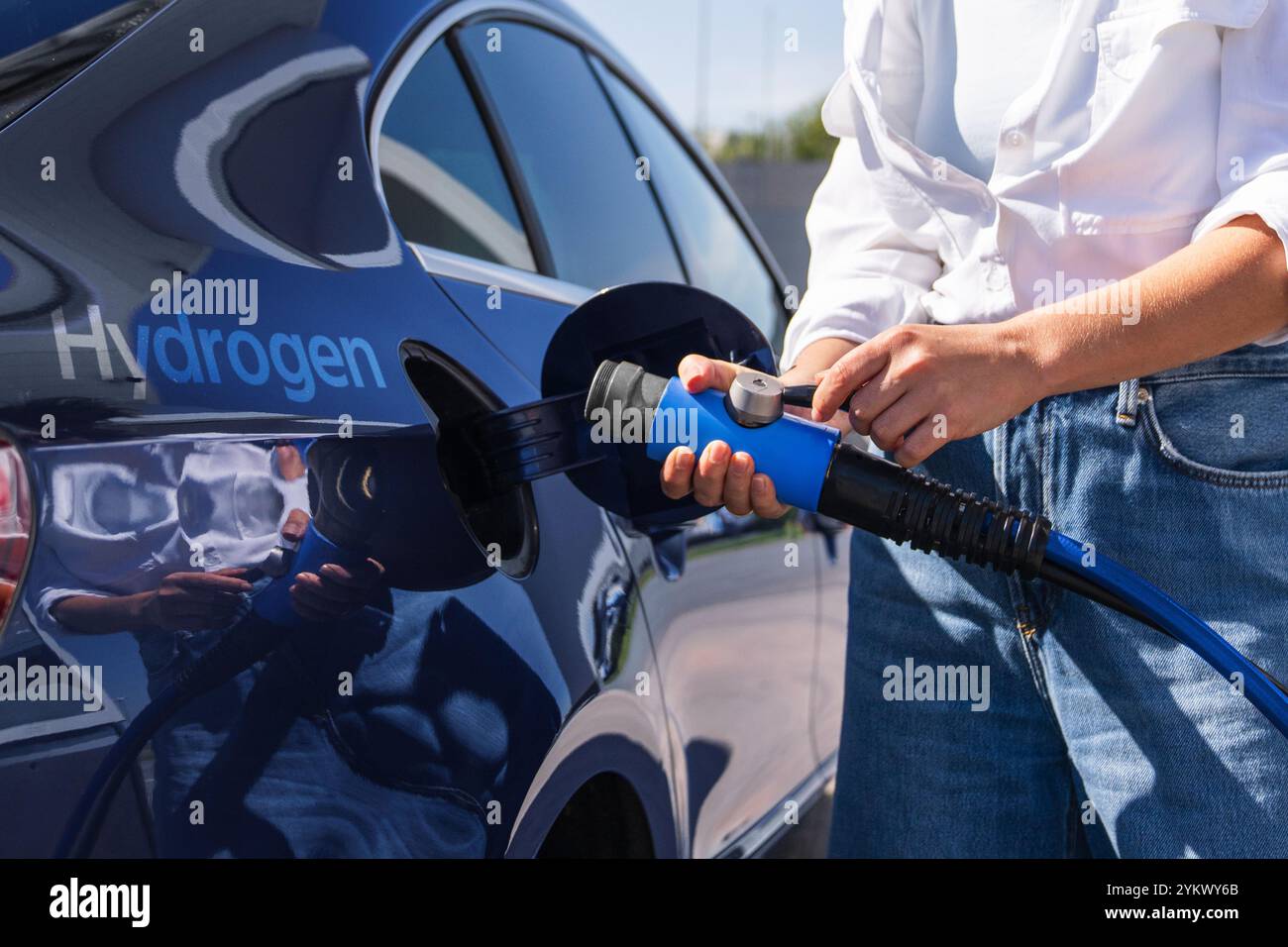 Woman holds a hydrogen fueling nozzle on a hydrogen filling station ...