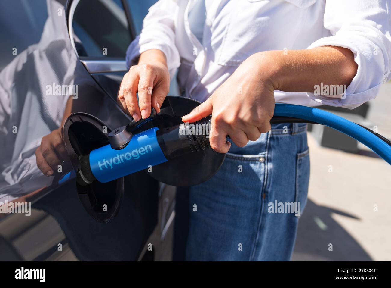 Woman holds a hydrogen fueling nozzle on a hydrogen filling station ...
