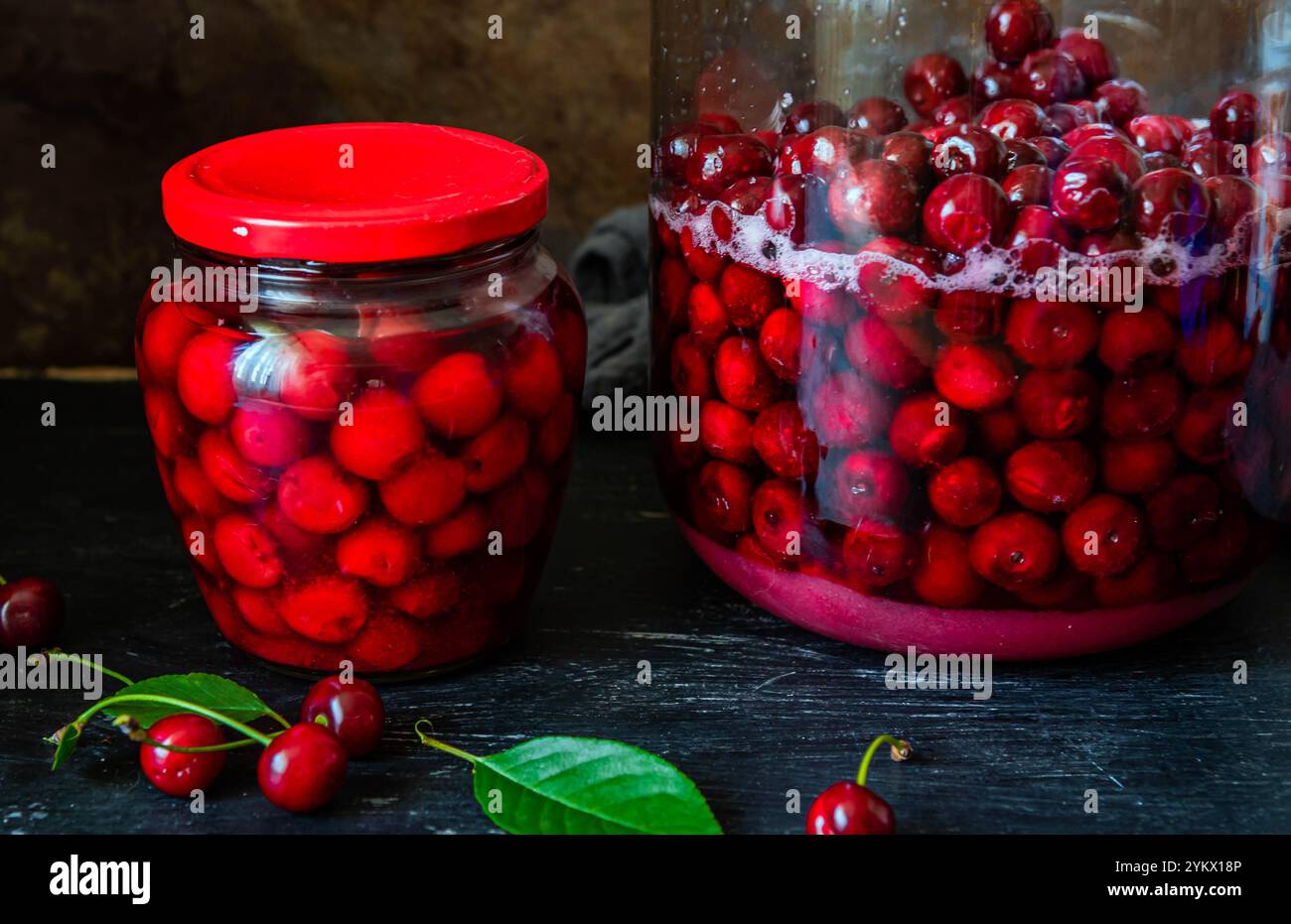 Homemade cherry preserves in a glass jar and fresh pitted red cherries ...