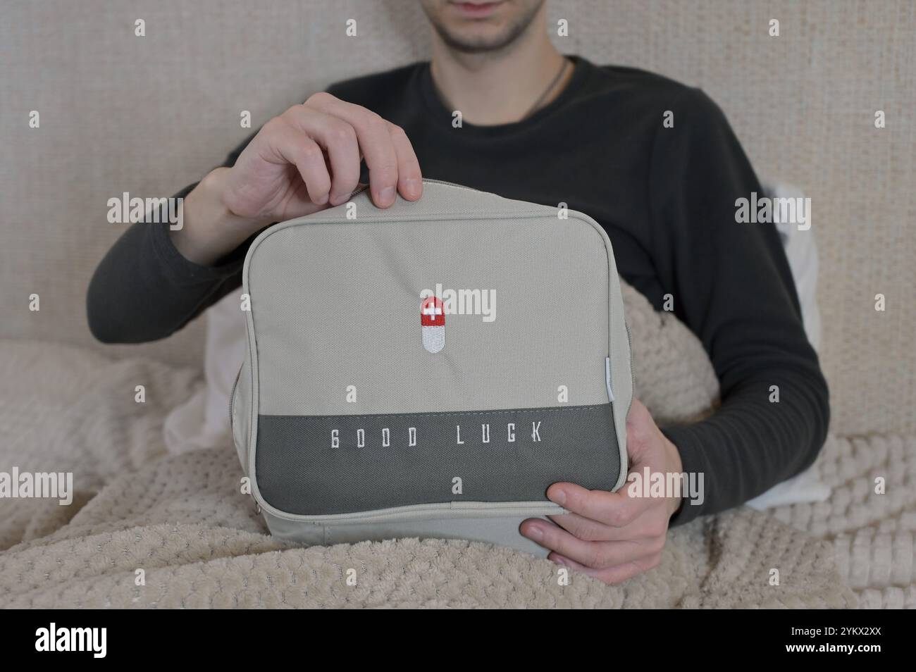 Man opening gray home first aid kit while sitting in bed Stock Photo ...