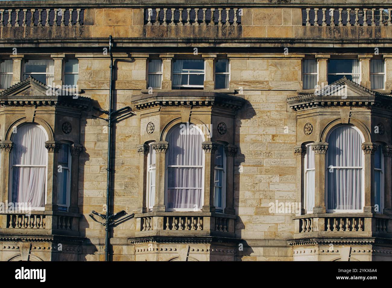 Beige stone building facade with three matching arched bay windows ...
