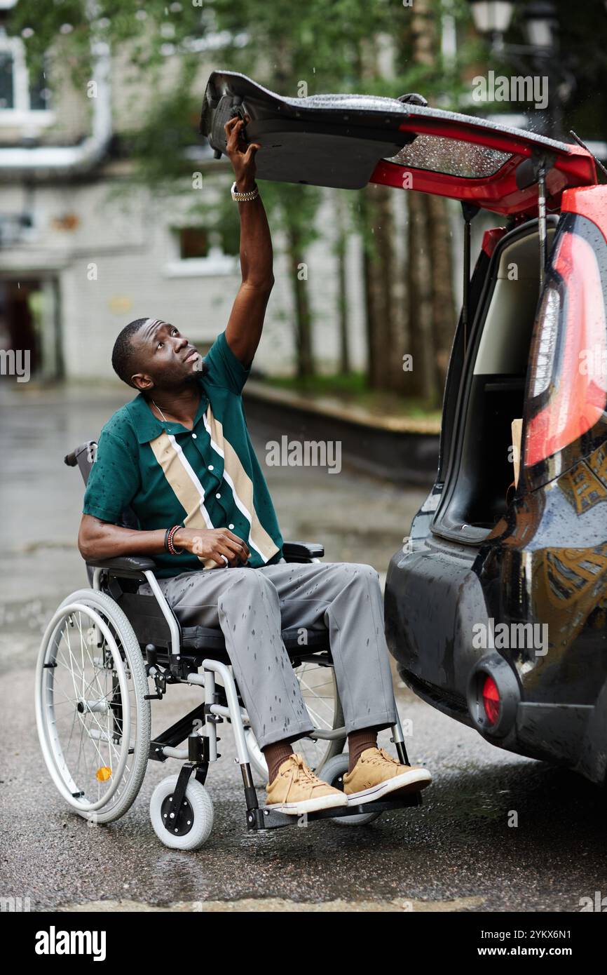 Vertical portrait of young African American man with disability opening ...