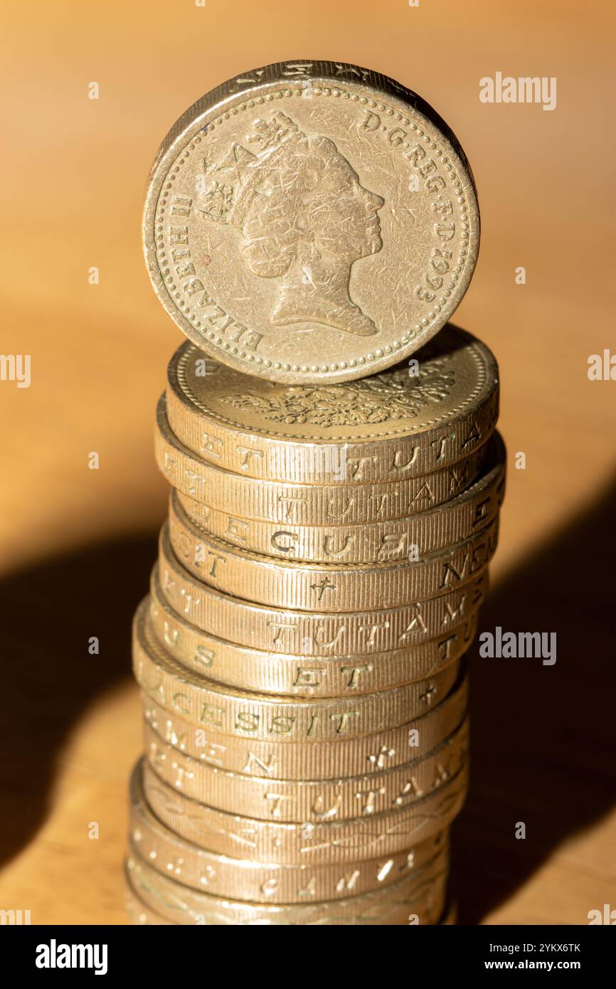 A stack of British one-pound coins, with a single coin balanced on top ...
