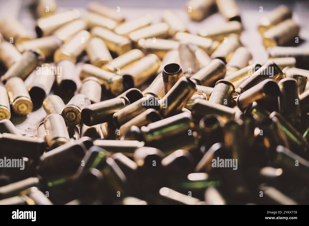The image shows a pile of spent bullet casings. They appear to be brass ...