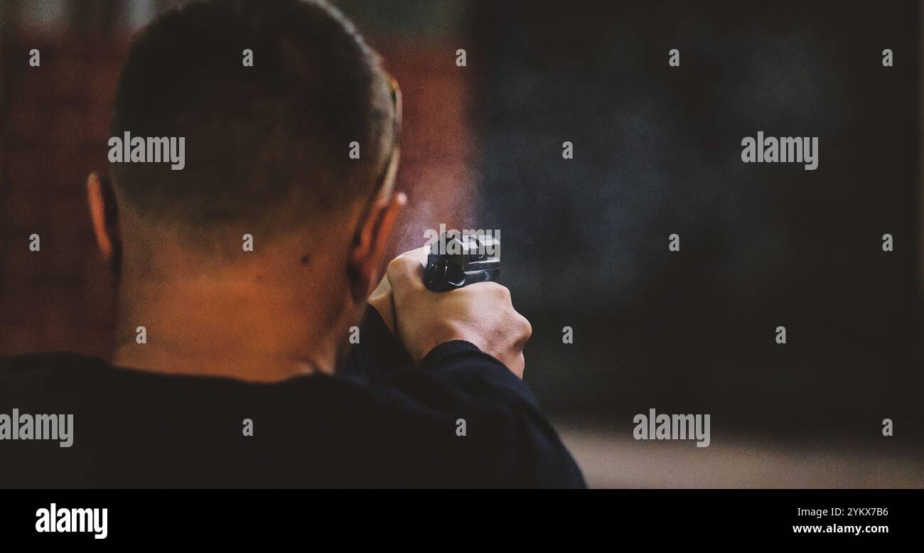 Man from the back aiming a handgun. The focus is on the firearm, which ...