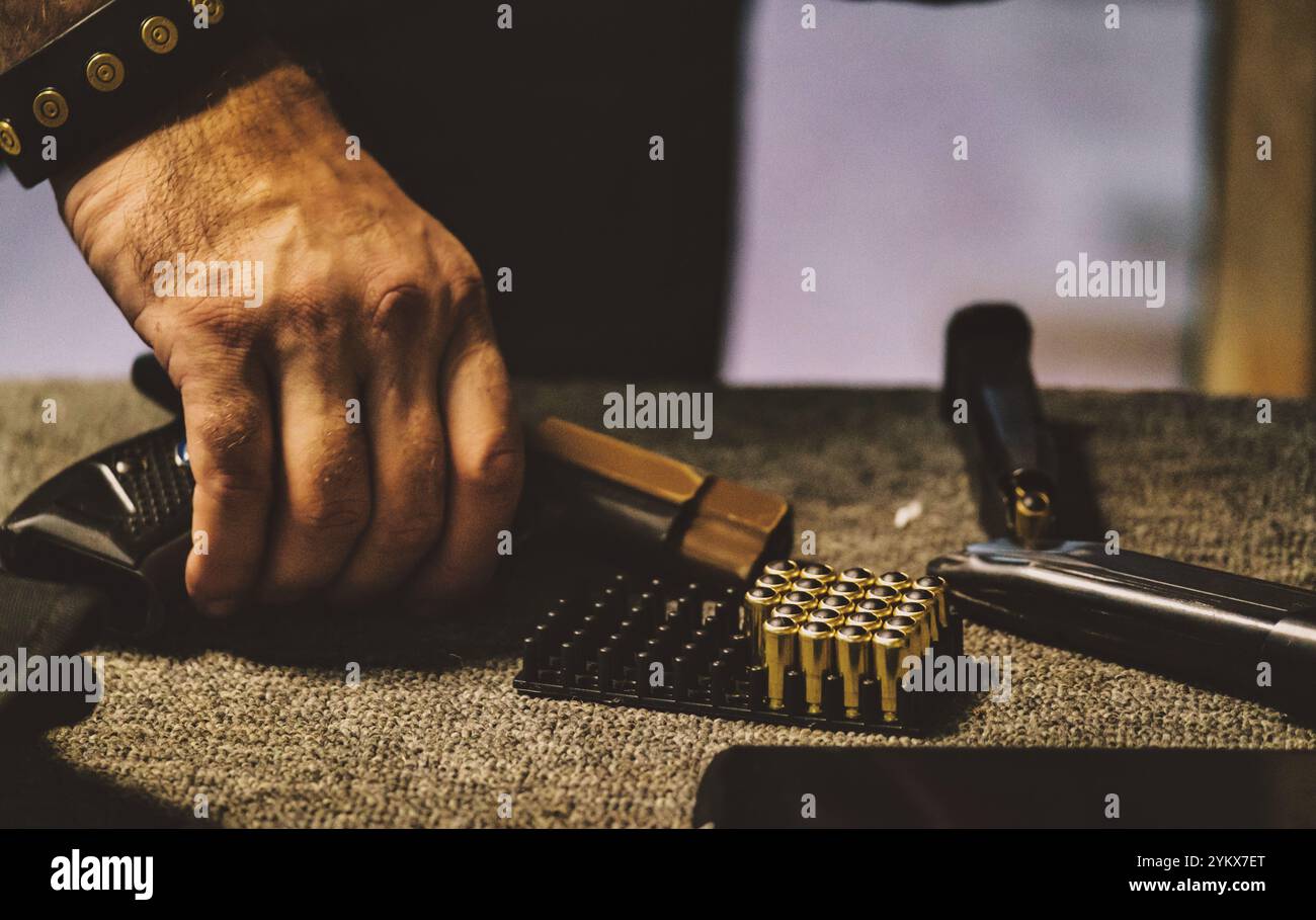 Man handling ammunition. There is a hand holding a handgun magazine ...