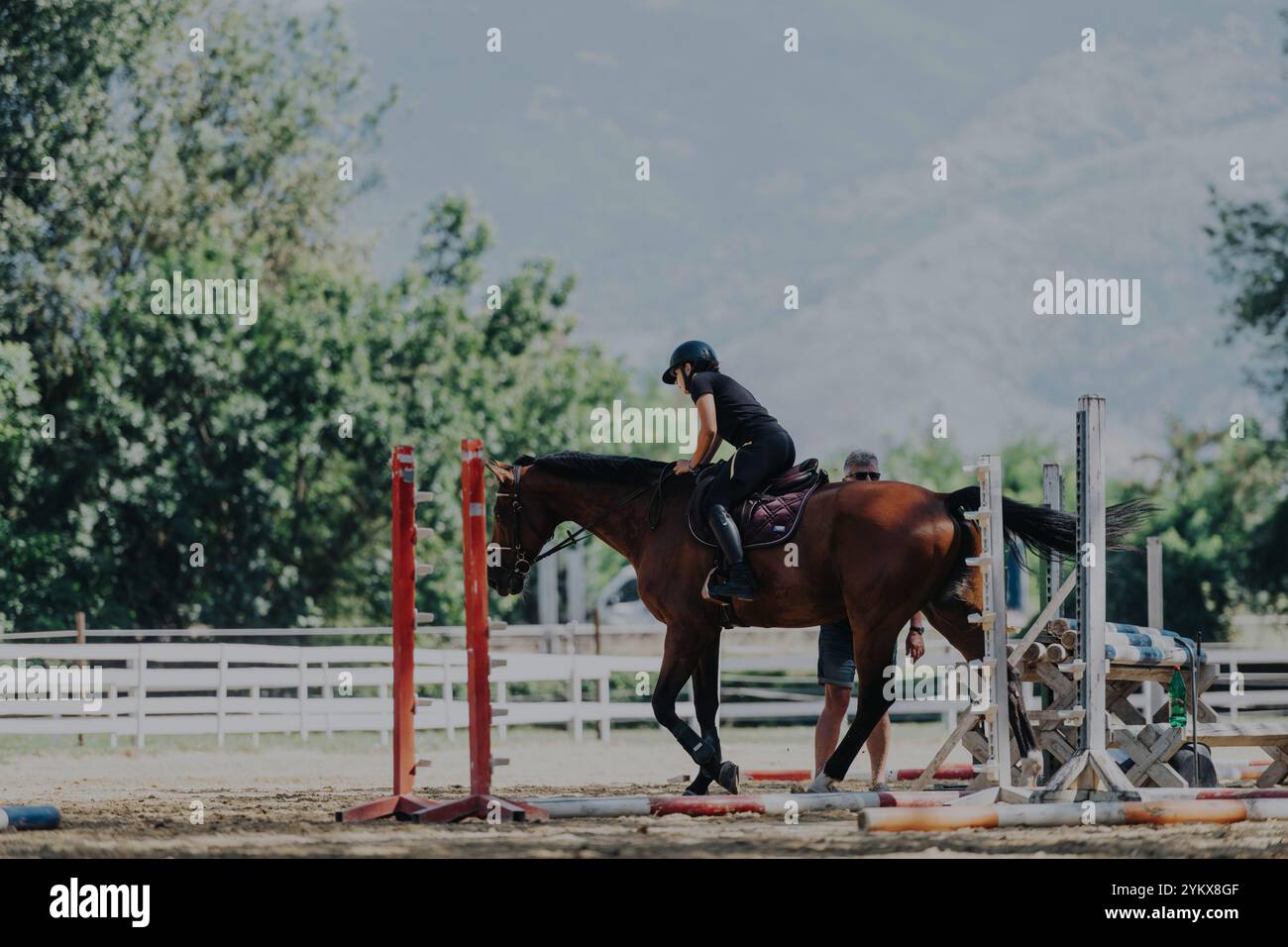 Young equestrian practicing horse jumping in outdoor riding arena Stock ...