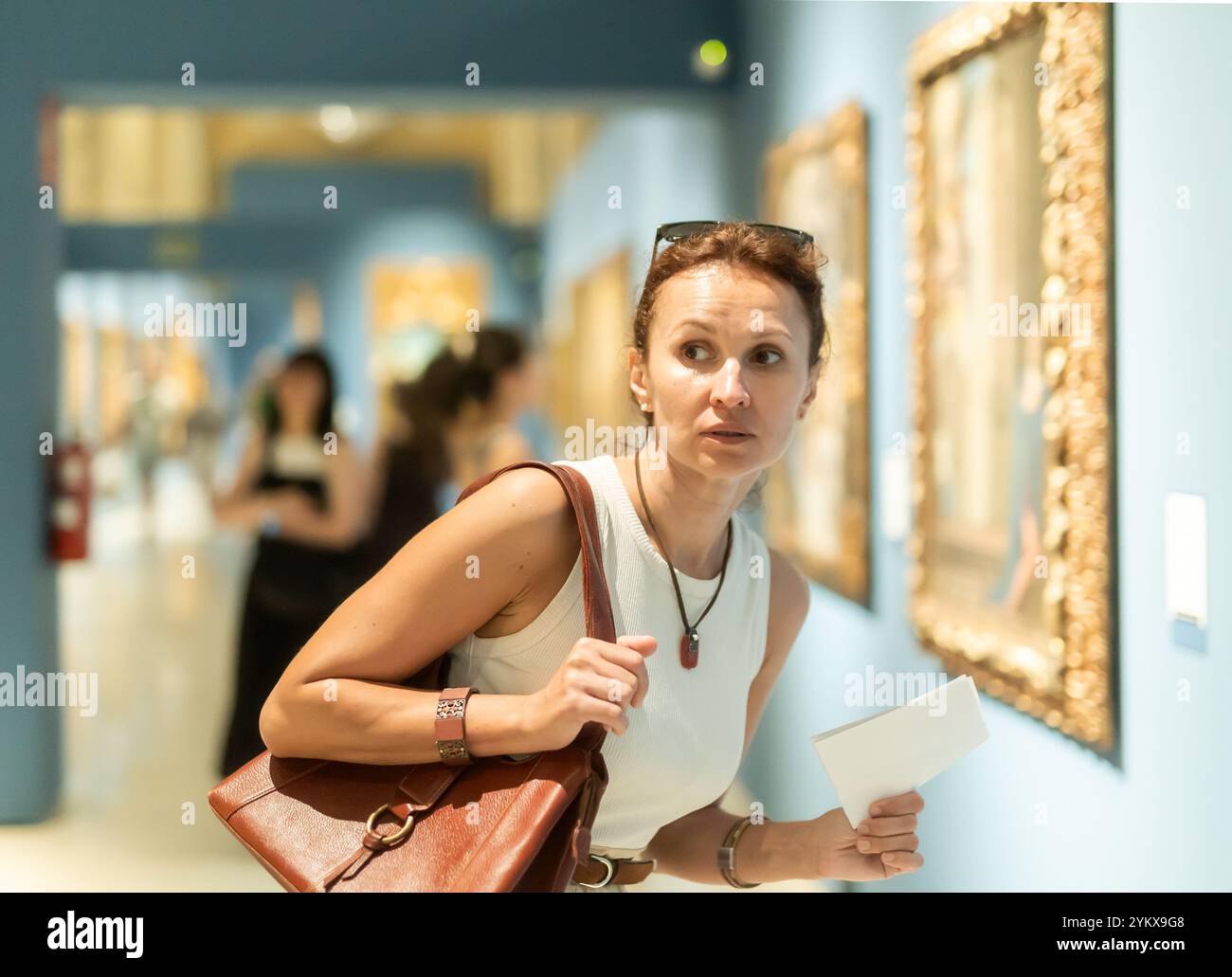Woman viewing art gallery with brochure Stock Photo - Alamy
