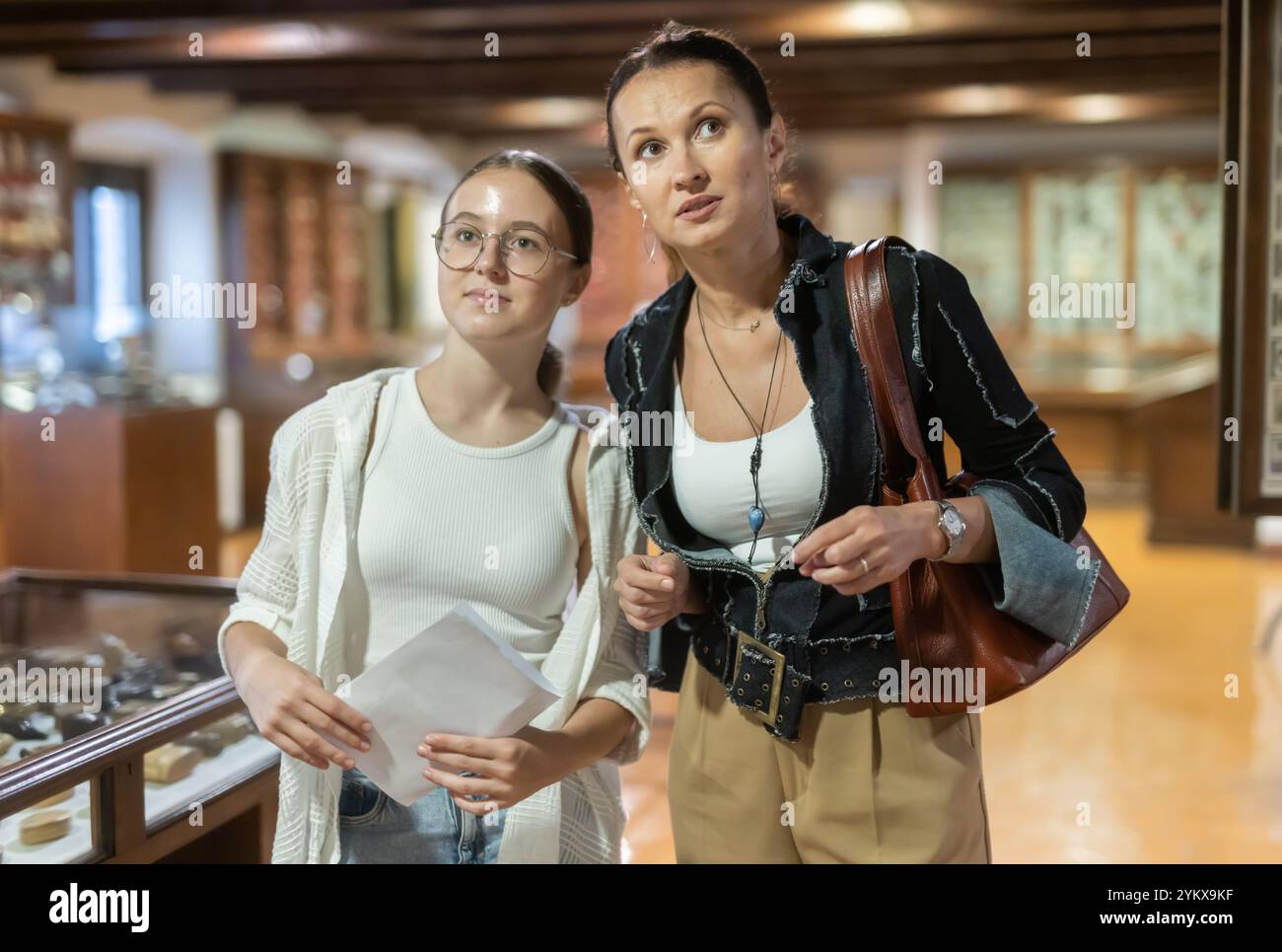 Young woman with teen daughter walk around museum, view antique ...