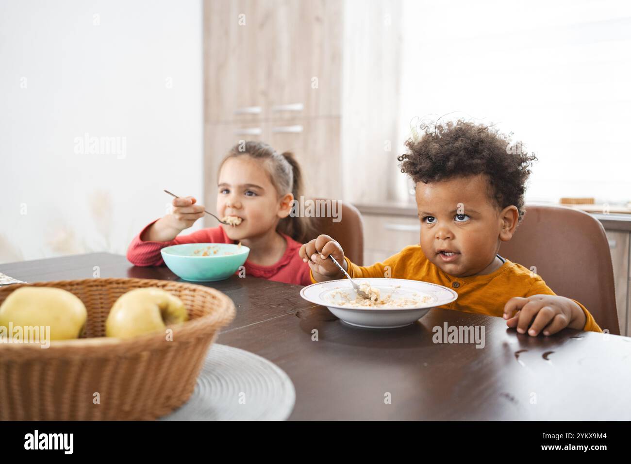 Multiracial children enjoy breakfast together at home during morning ...