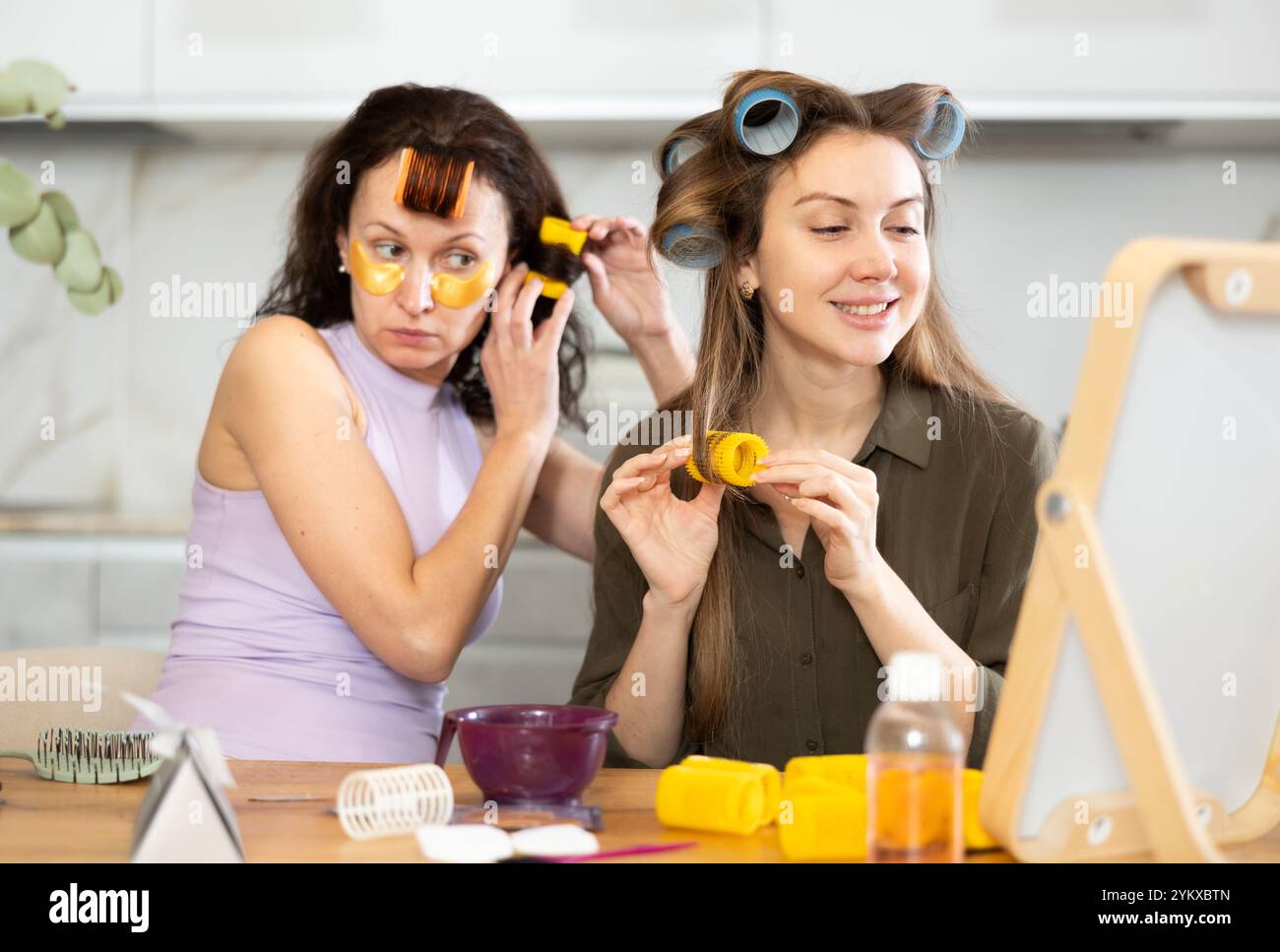 Female friends curling hair with rollers by tabletop mirror Stock Photo ...
