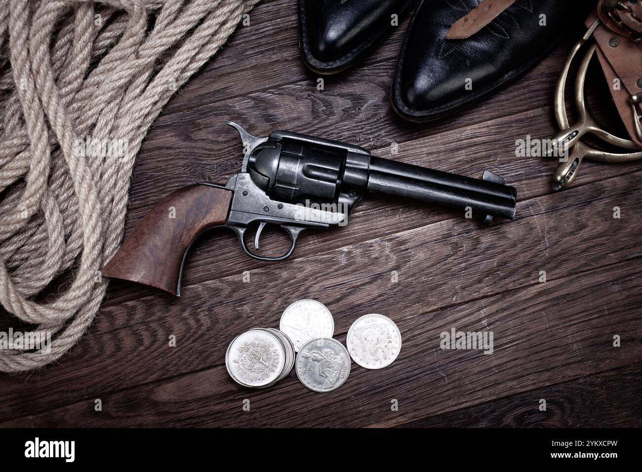 Old western revolver gun with silver dollars and cowboy boots on wooden ...