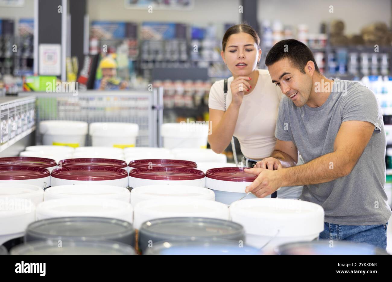 Husband and wife choose a can of paint together at hardware store Stock ...