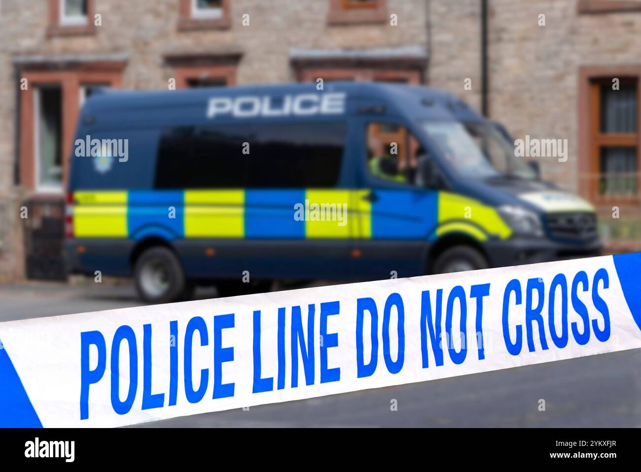 Blue and white police line do not cross crime scene tape in focus with ...