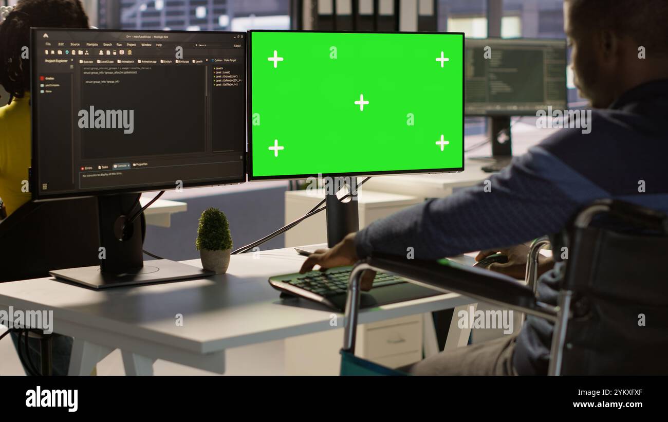 Developer with disability sitting in wheelchair fixing applications issues on green screen PC ...