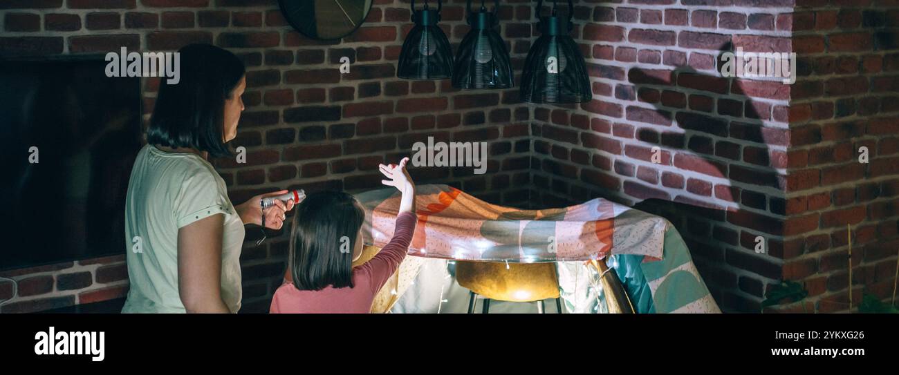 Banner of mother holding flashlight while daughter making shadow ...
