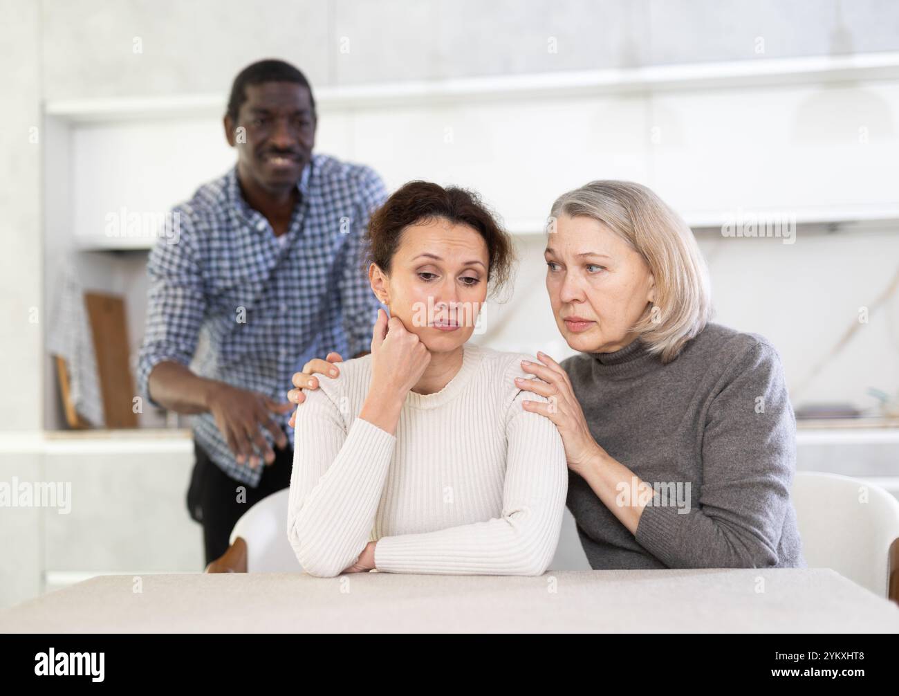 Old woman trying to calm angry middle-aged woman while man quarreling ...