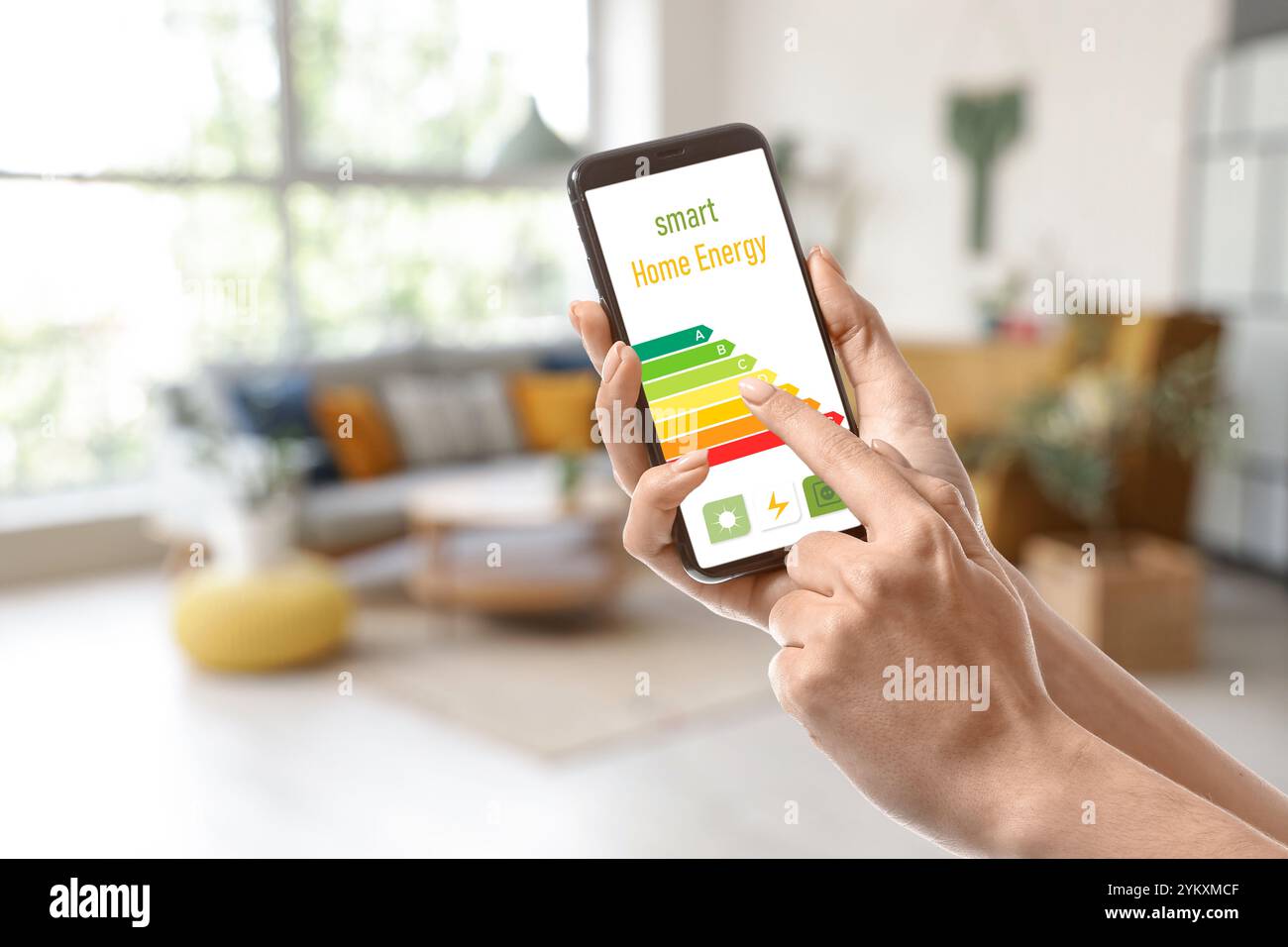 Hands holding mobile phone with energy efficiency rating on screen in ...